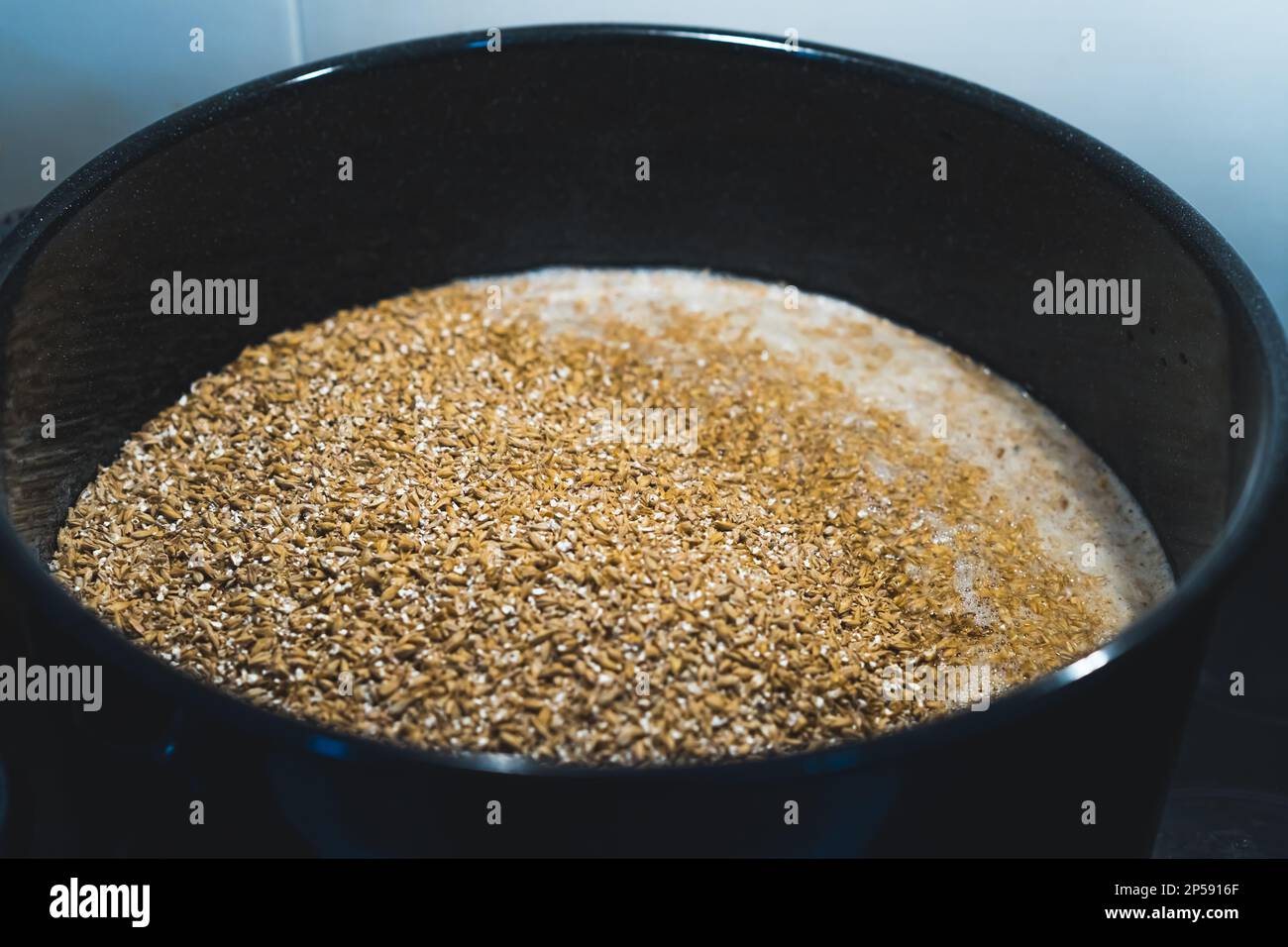 Adding malt to water for sweetening process in a big pot. High quality ...