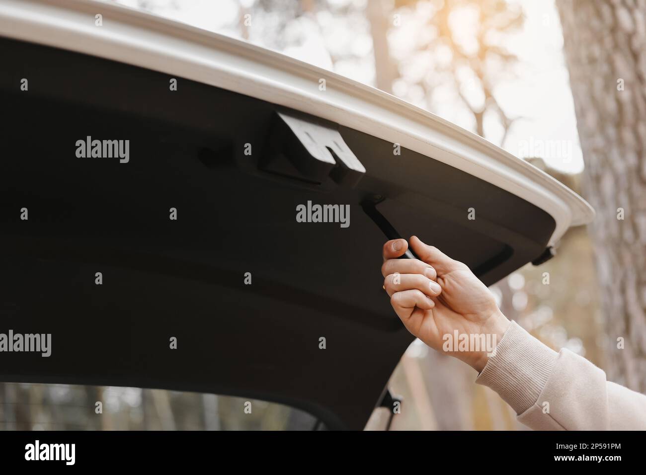Unrecognisable man holds trunk handle and closes car trunk door ...