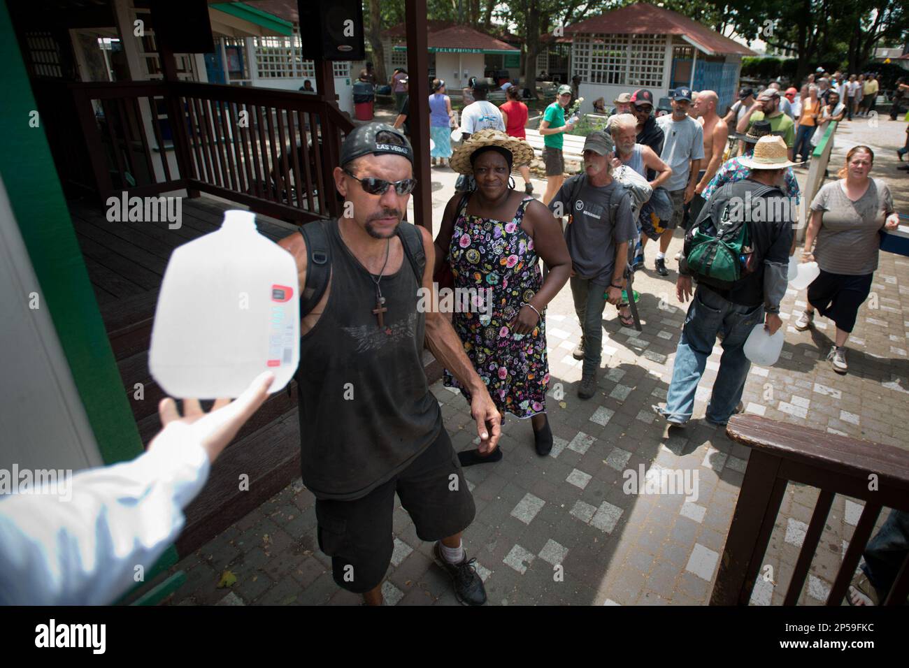 John Parilo, from the Mayor's office, hands a gallon jug of donated ...