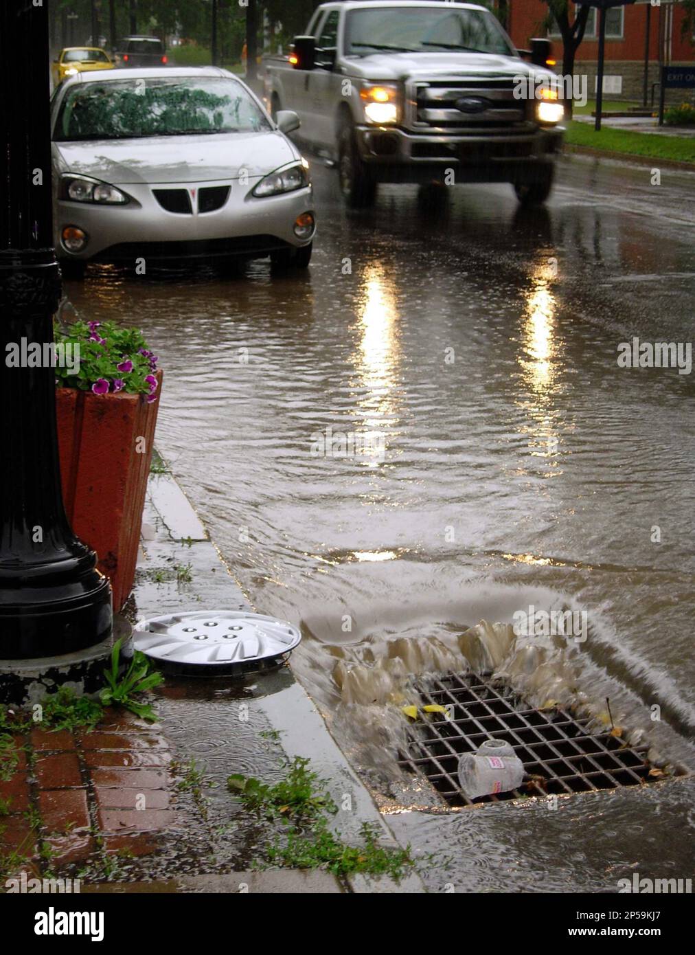 Water pours down a storm drain during heavy rain on Main Street in ...