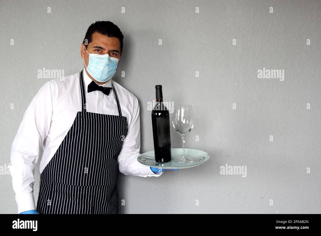 Latin bartender somelier with red wine, face masks and latex gloves ...