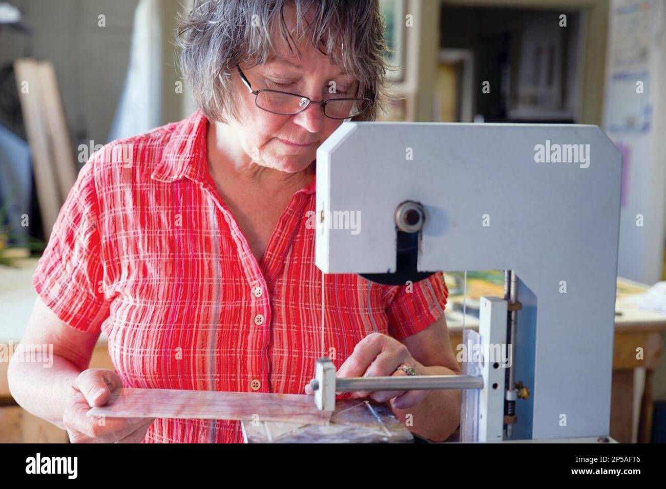 In this June 12, 2013 photo, Paulette Kucera cuts a piece of glass with ...