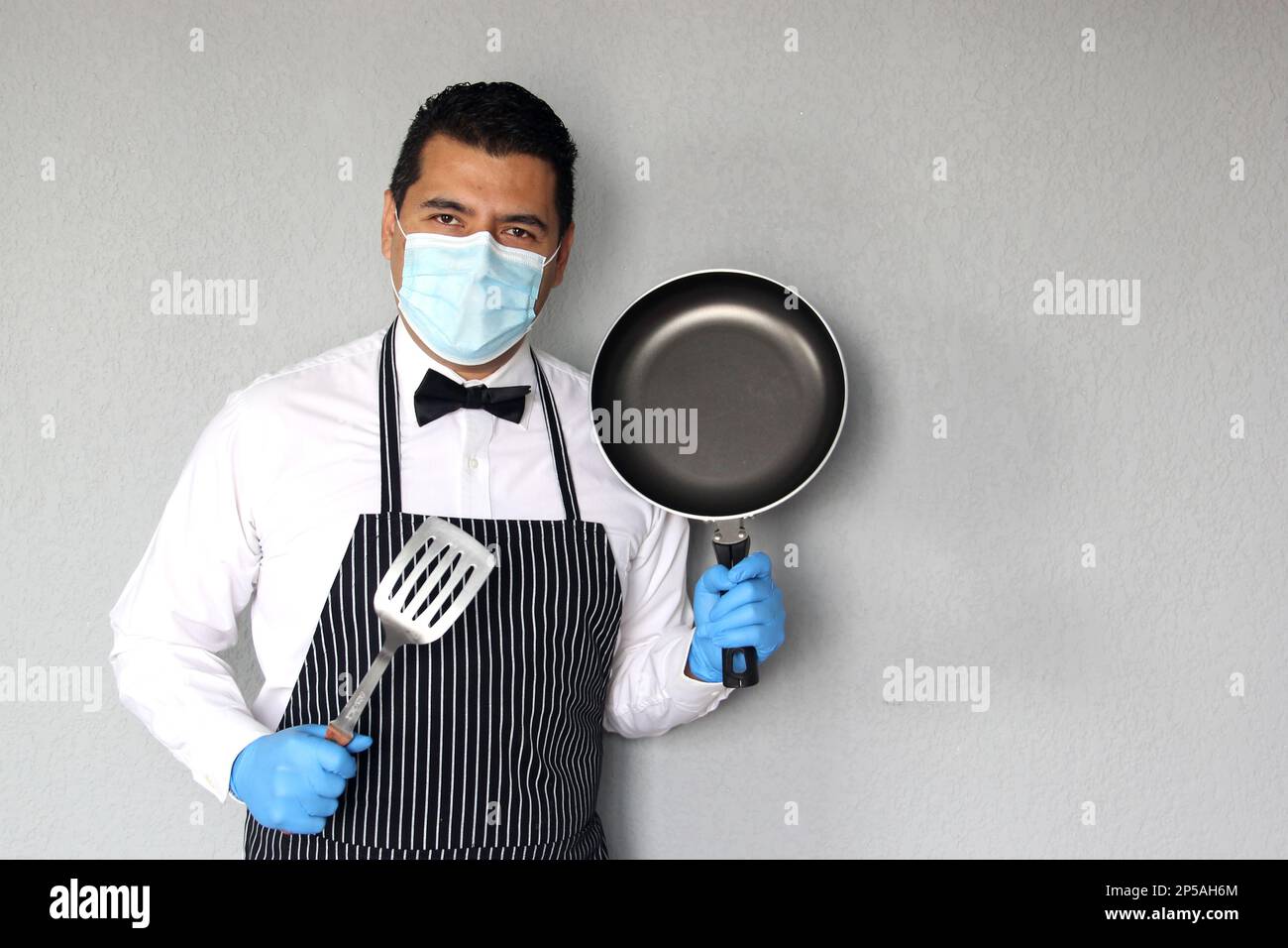 Latino chef with kitchen utensils working with mouth mask and latex ...