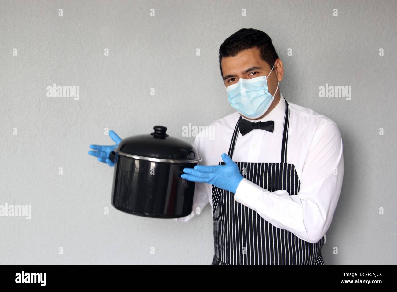 Latino chef with kitchen utensils working with mouth mask and latex ...