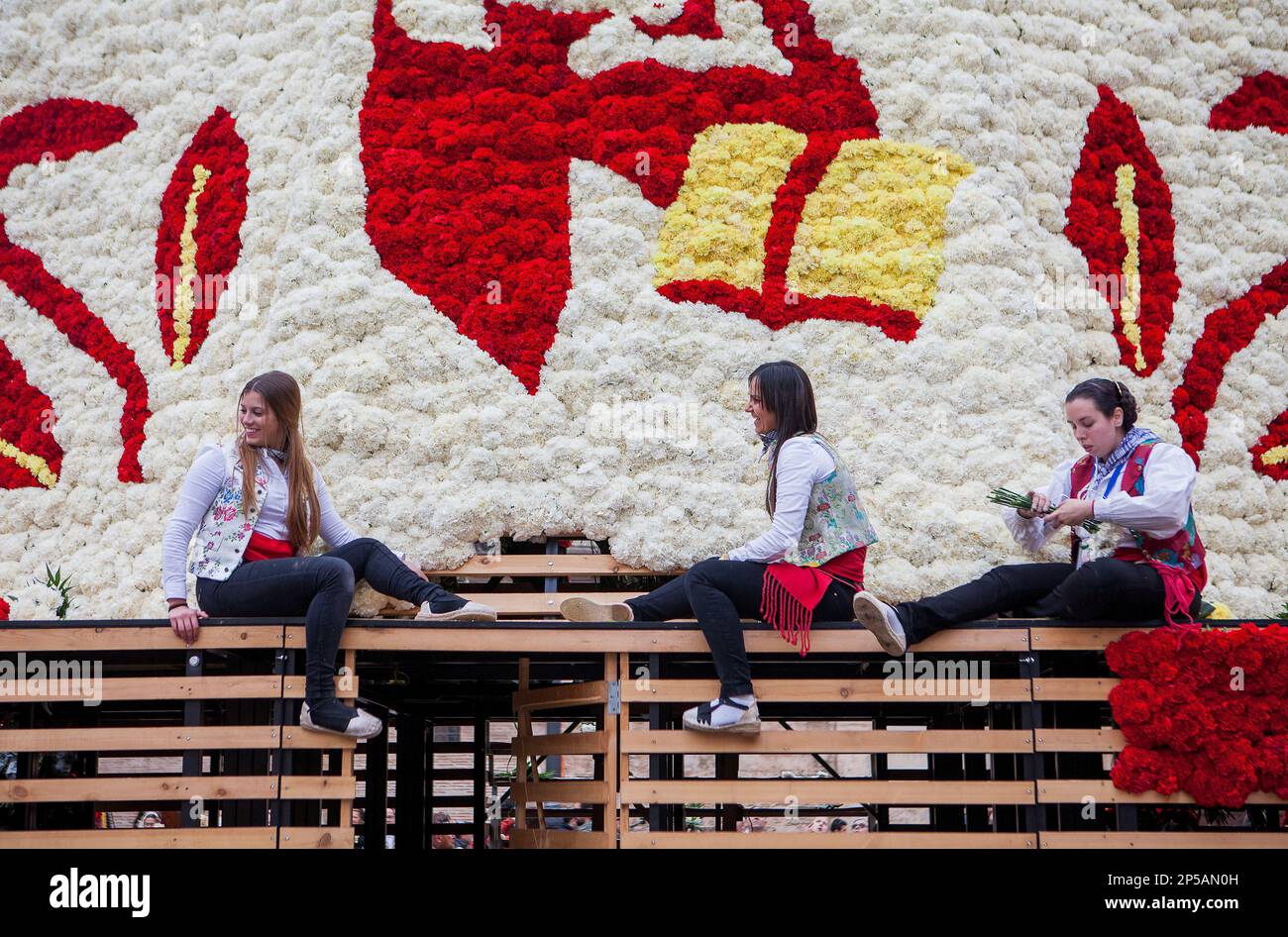 Women placing flower offerings on large wooden replica statue of Virgen ...