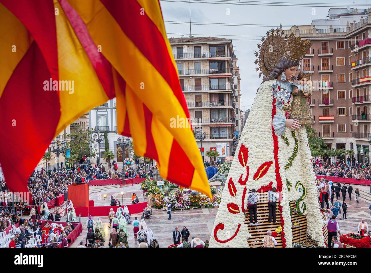 Men placing flower offerings on large wooden replica statue of Virgen ...