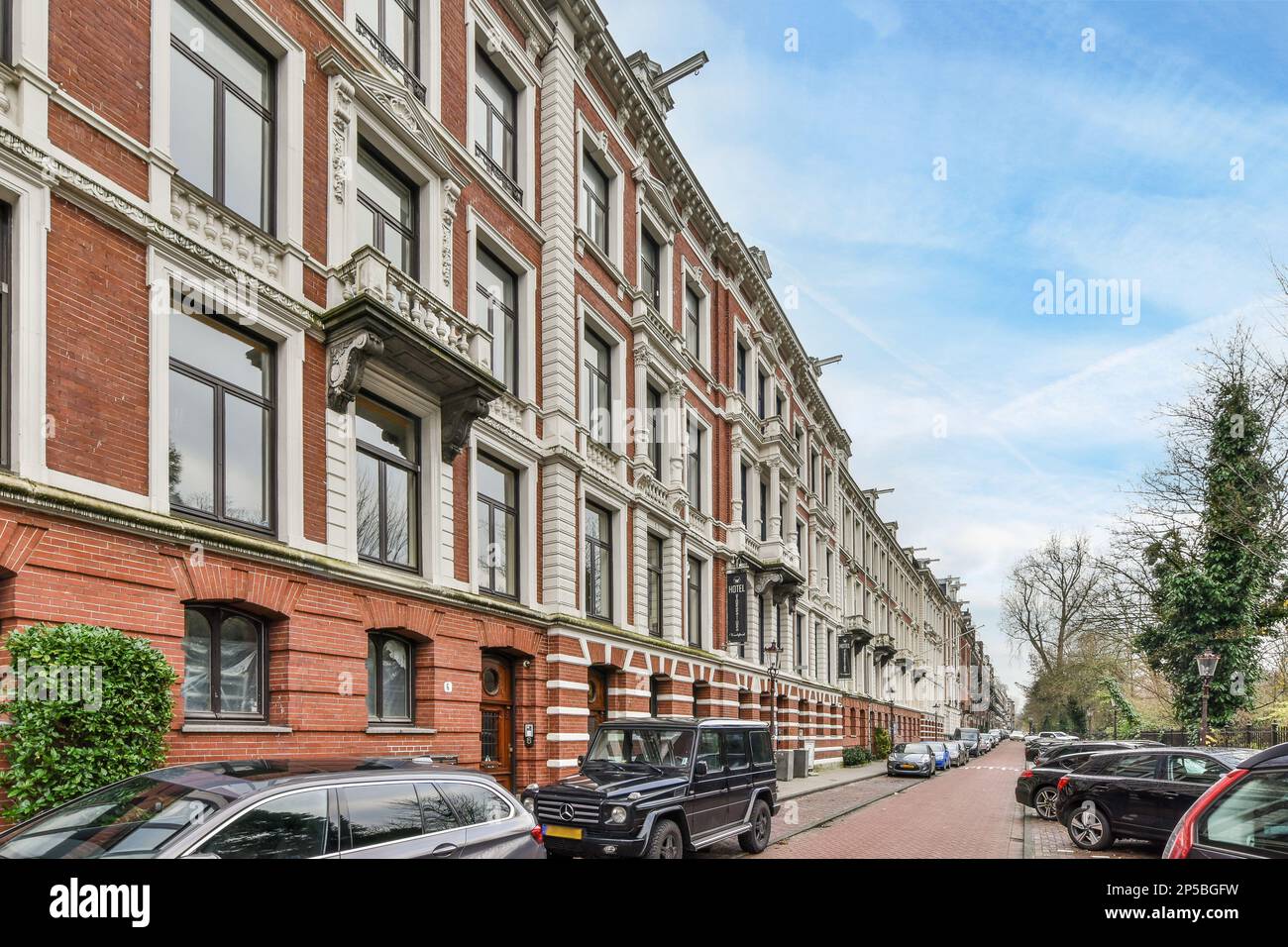 some cars parked on the side of the road in front of a large red brick ...