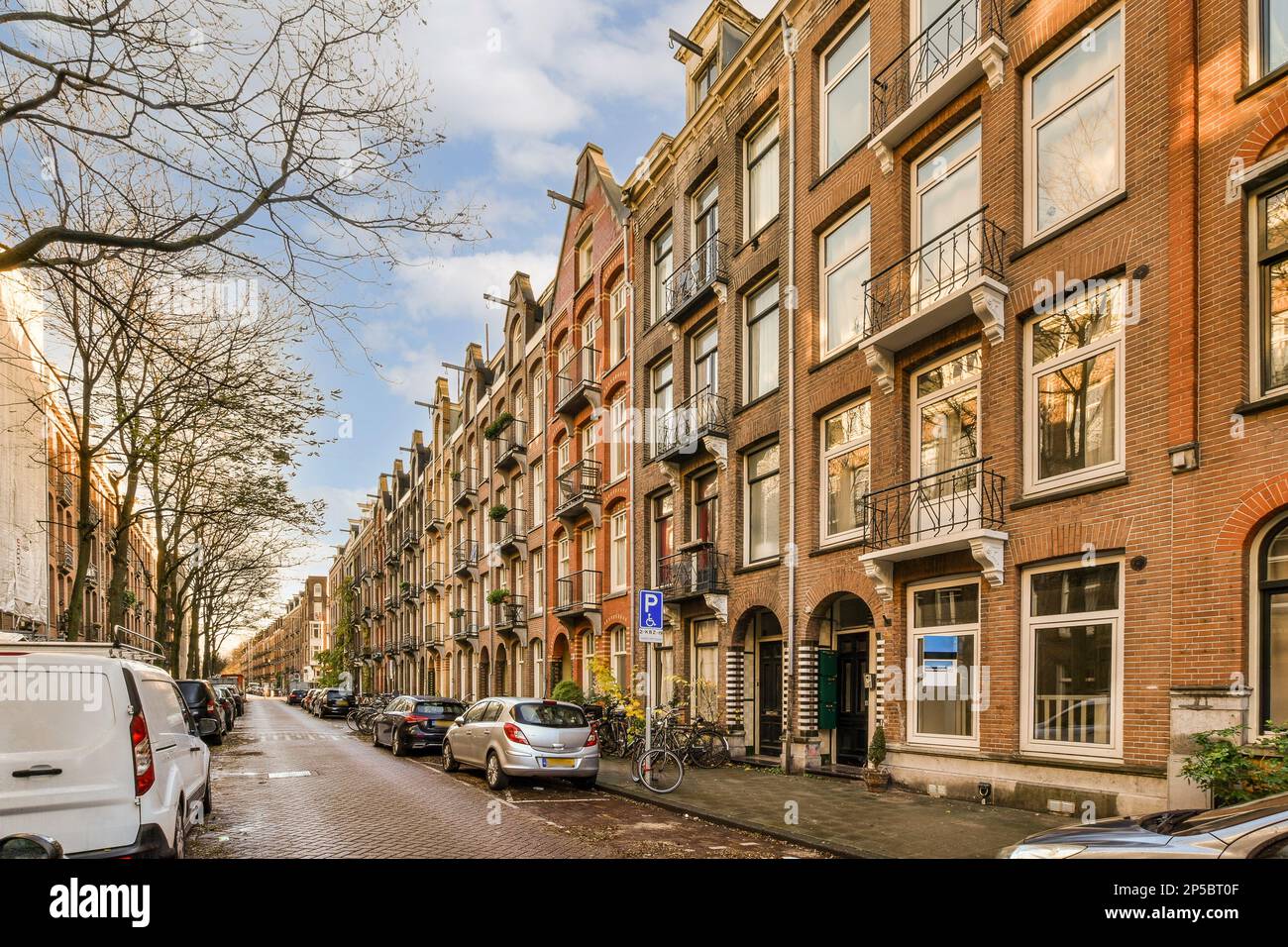 a city street with cars parked on the side and buildings in the back ...