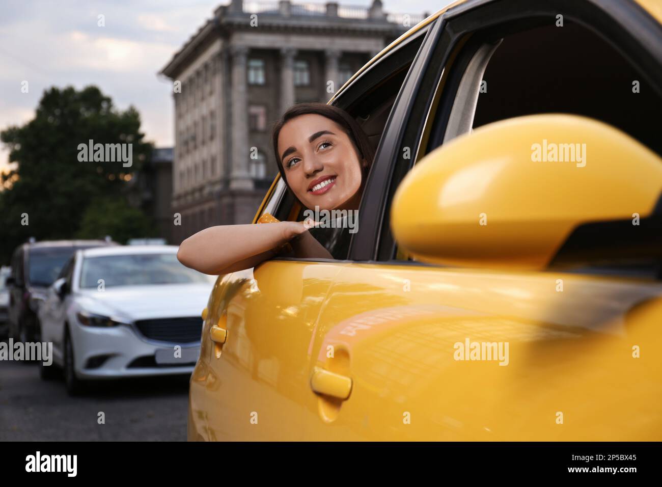 Beautiful young woman looking out of taxi window outdoors Stock Photo ...