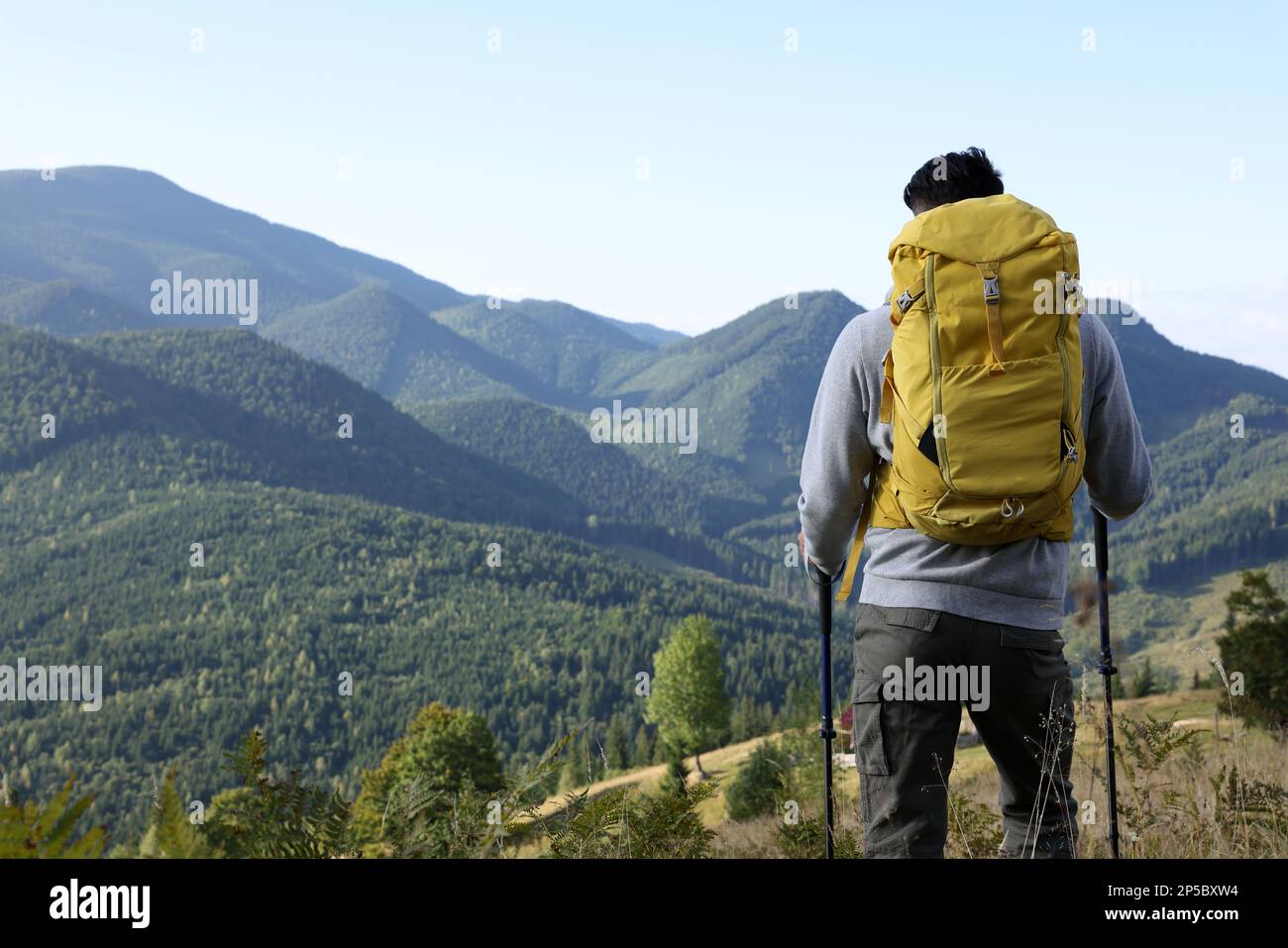 Tourist with backpack and trekking poles enjoying mountain landscape ...