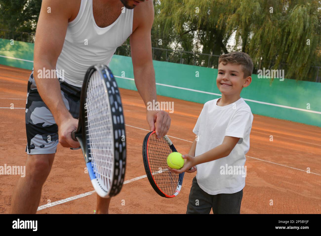 Father teaching son to play tennis on court Stock Photo - Alamy