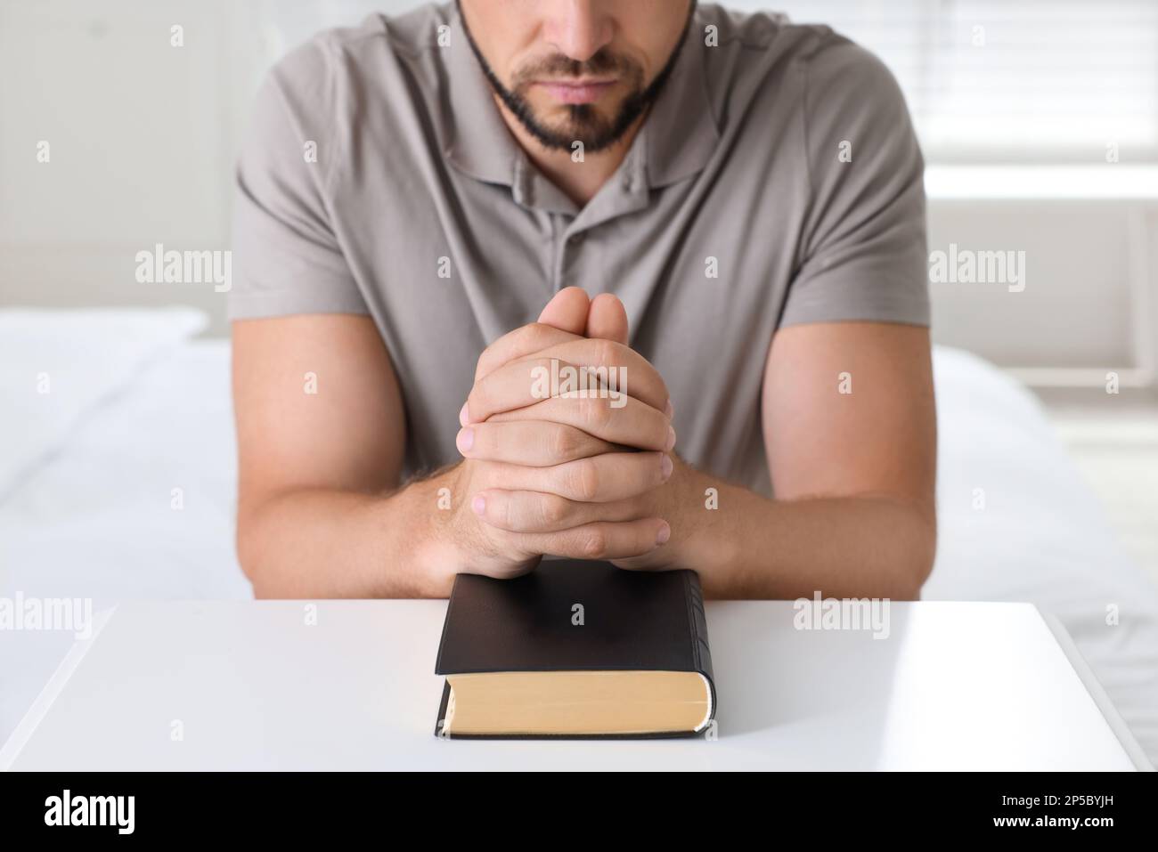 Religious man with Bible praying at home, closeup Stock Photo - Alamy
