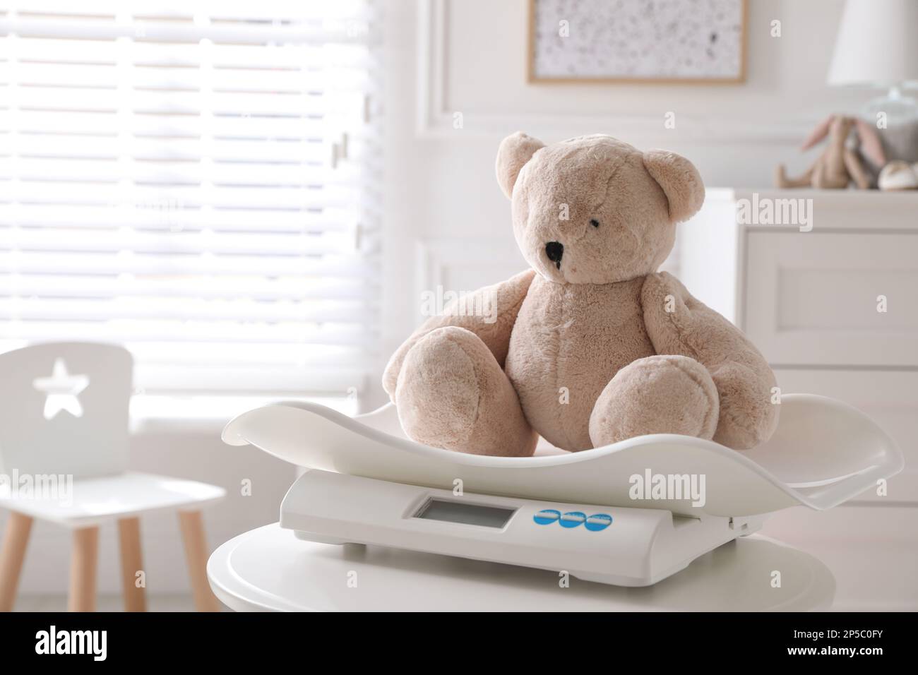 Baby scales with teddy bear on table in room Stock Photo - Alamy