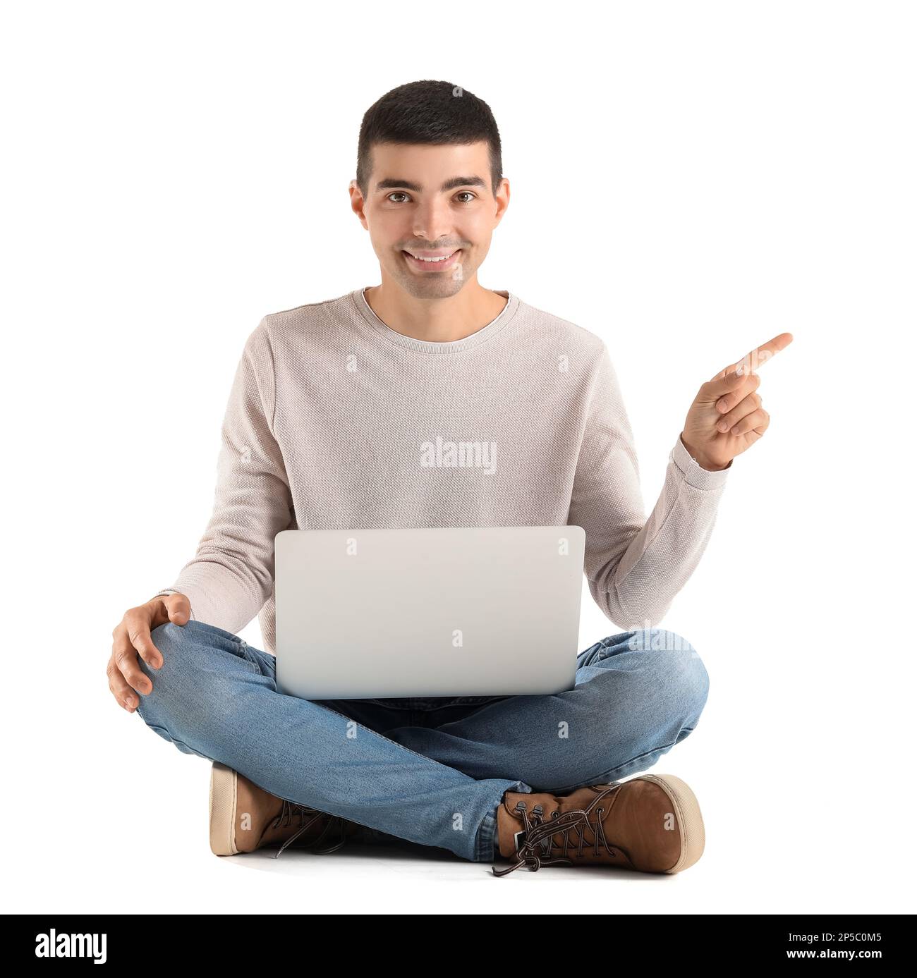 Handsome guy with laptop pointing at something on white background ...