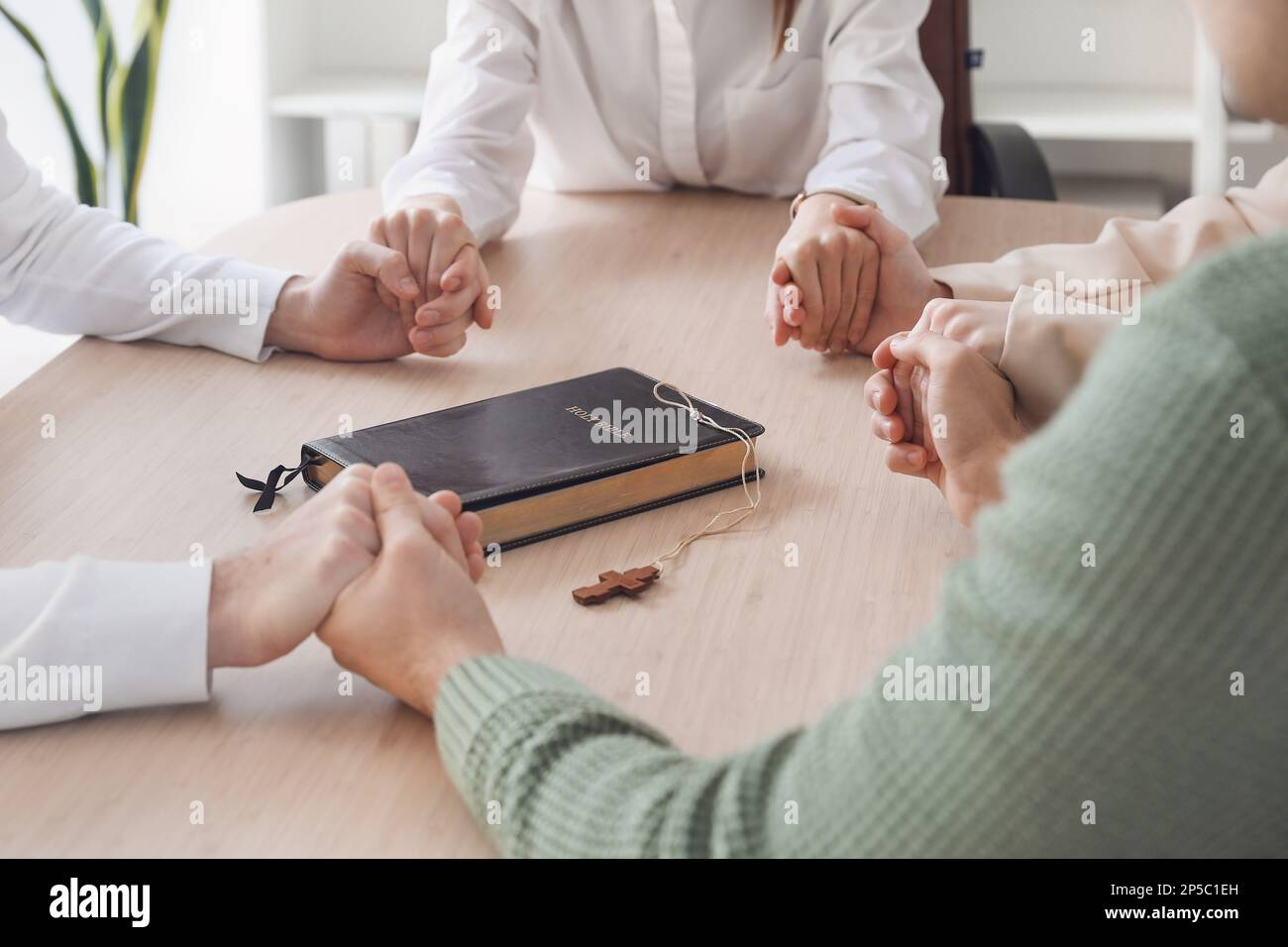 Group of business people praying with Holy Bible at table in office ...