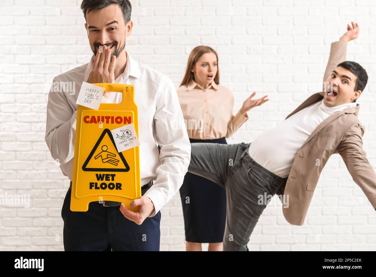 Young man with caution sign playing a prank on his colleagues against ...