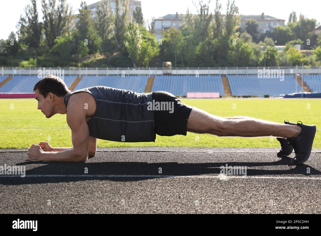 Sporty man doing plank exercise at stadium Stock Photo - Alamy