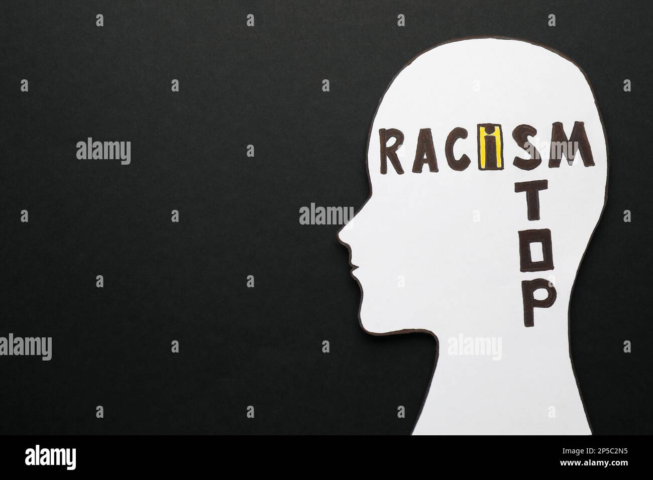 Human head cutout and phrase Stop Racism on black background, top view ...