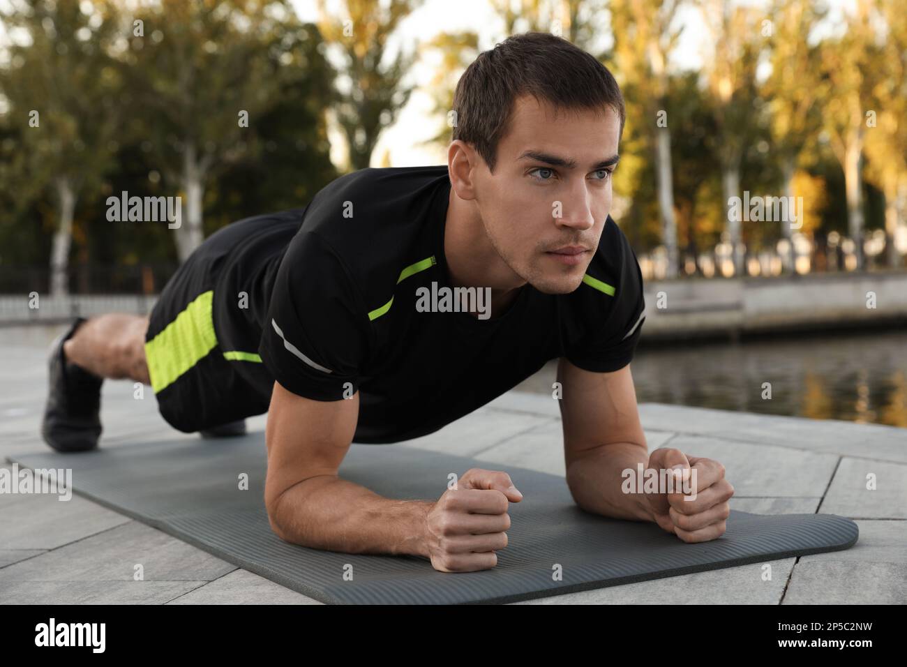 Sporty man doing plank exercise on mat outdoors Stock Photo - Alamy
