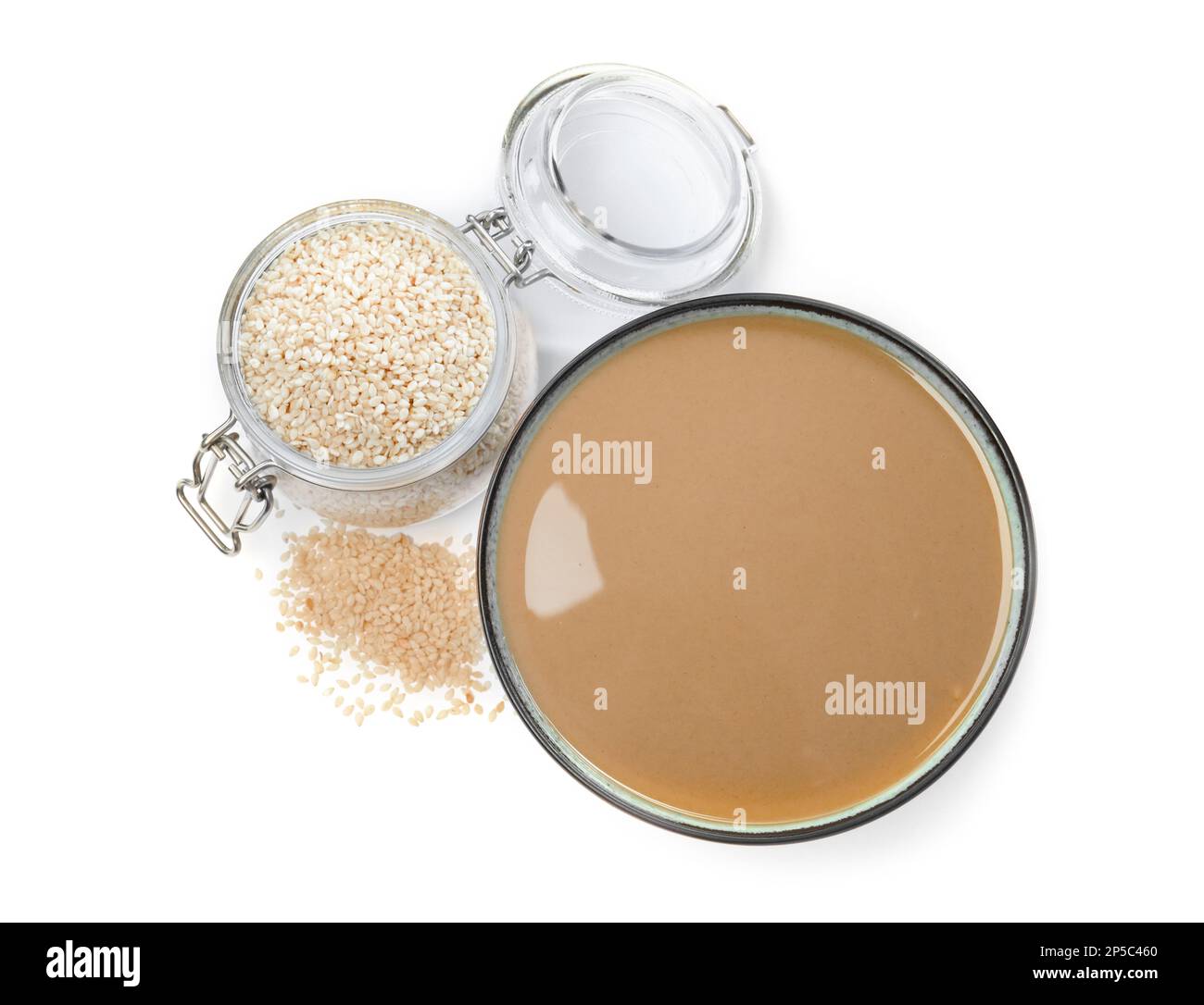 Bowl of tasty sesame paste, jar and seeds on white background, top view ...