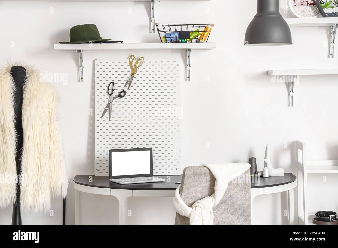 Interior of modern atelier with tailor's workplace, shelves and ...
