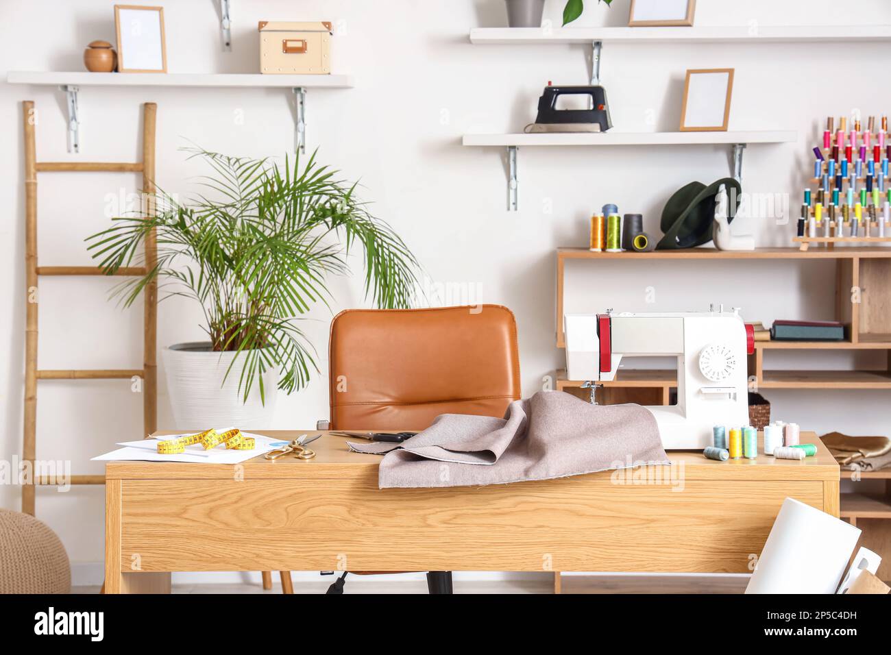 Tailor's workplace with sewing machine in interior of modern atelier ...