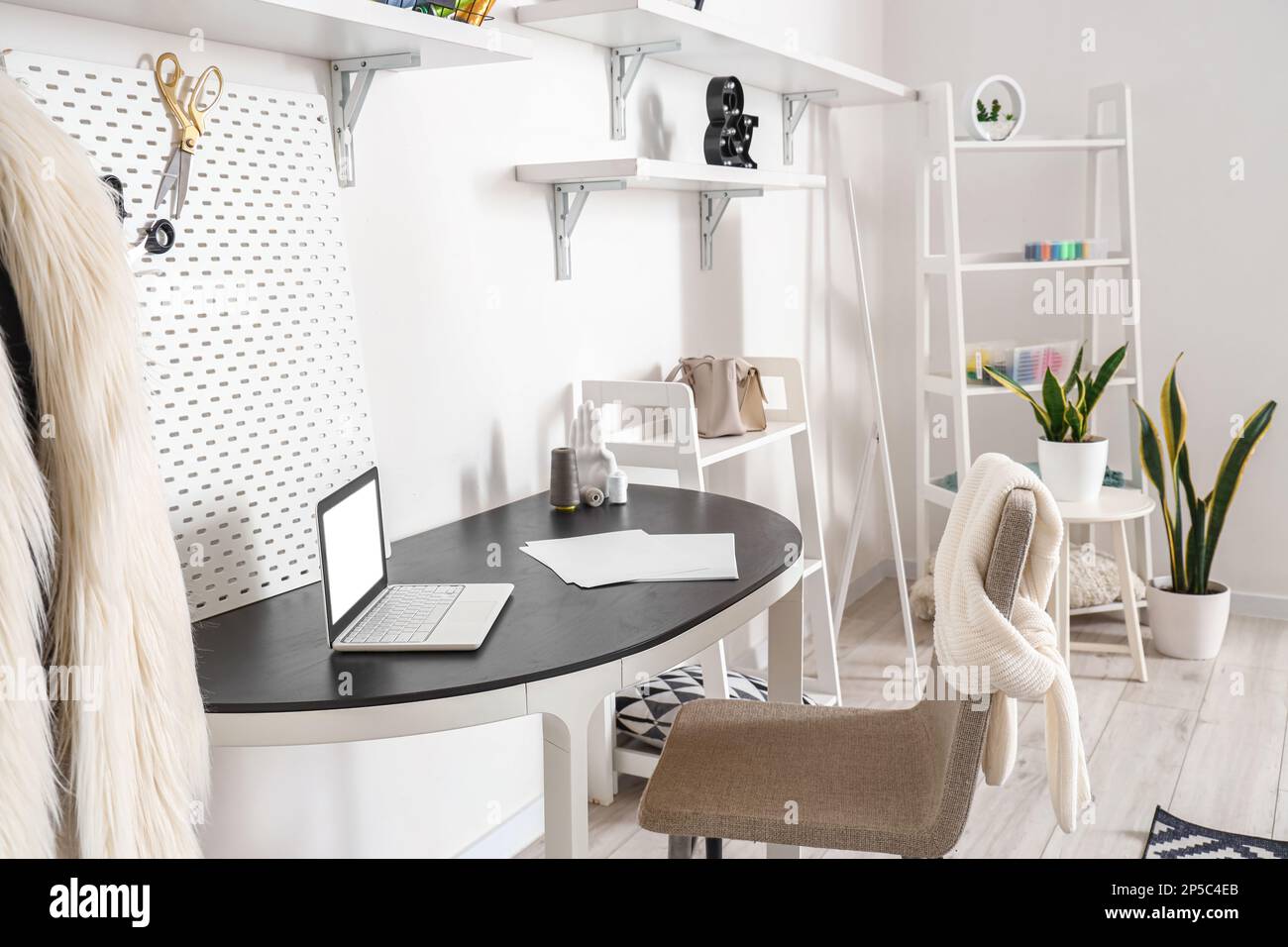 Interior of modern atelier with tailor's workplace, shelving units and ...