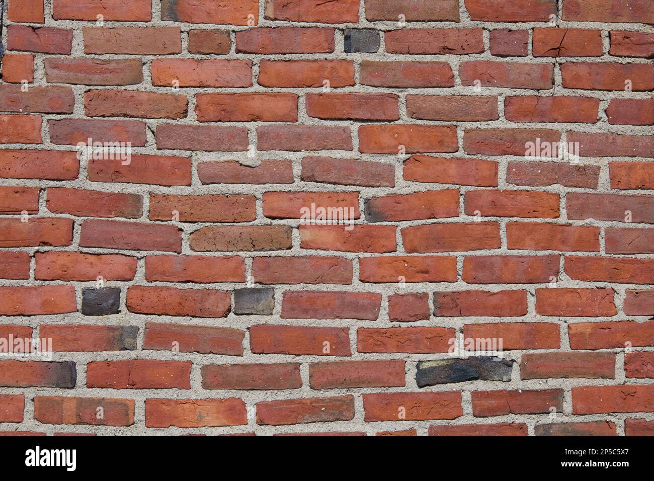 Old, red brick wall that has uneven, horizontal lines and has been ...
