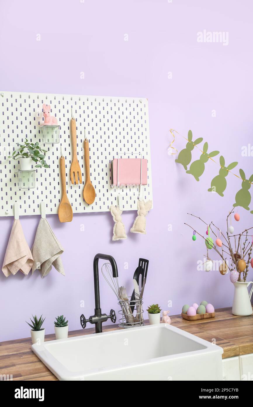 Pegboard with bunnies and Easter eggs on kitchen counter near lilac ...