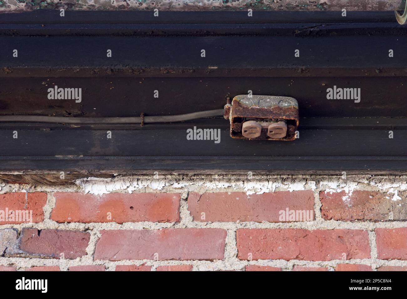 Red, brick wall with black trim on top, that has rusted electrical ...