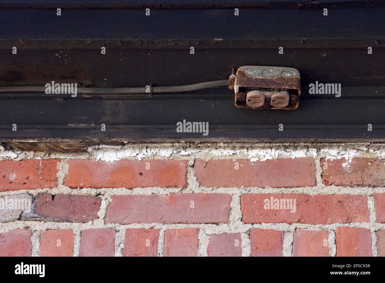 Red brick wall with black trim on top, that has rusted electrical ...