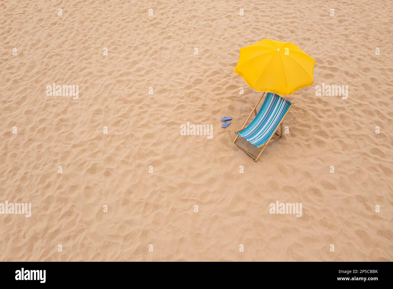 Yellow beach umbrella, sunbed and flip flops on sandy coast. Space for ...