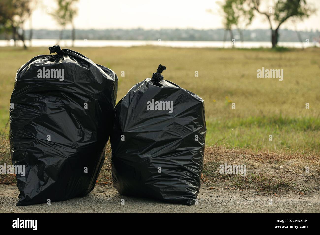 Trash bags full of garbage on pavement outdoors Stock Photo - Alamy
