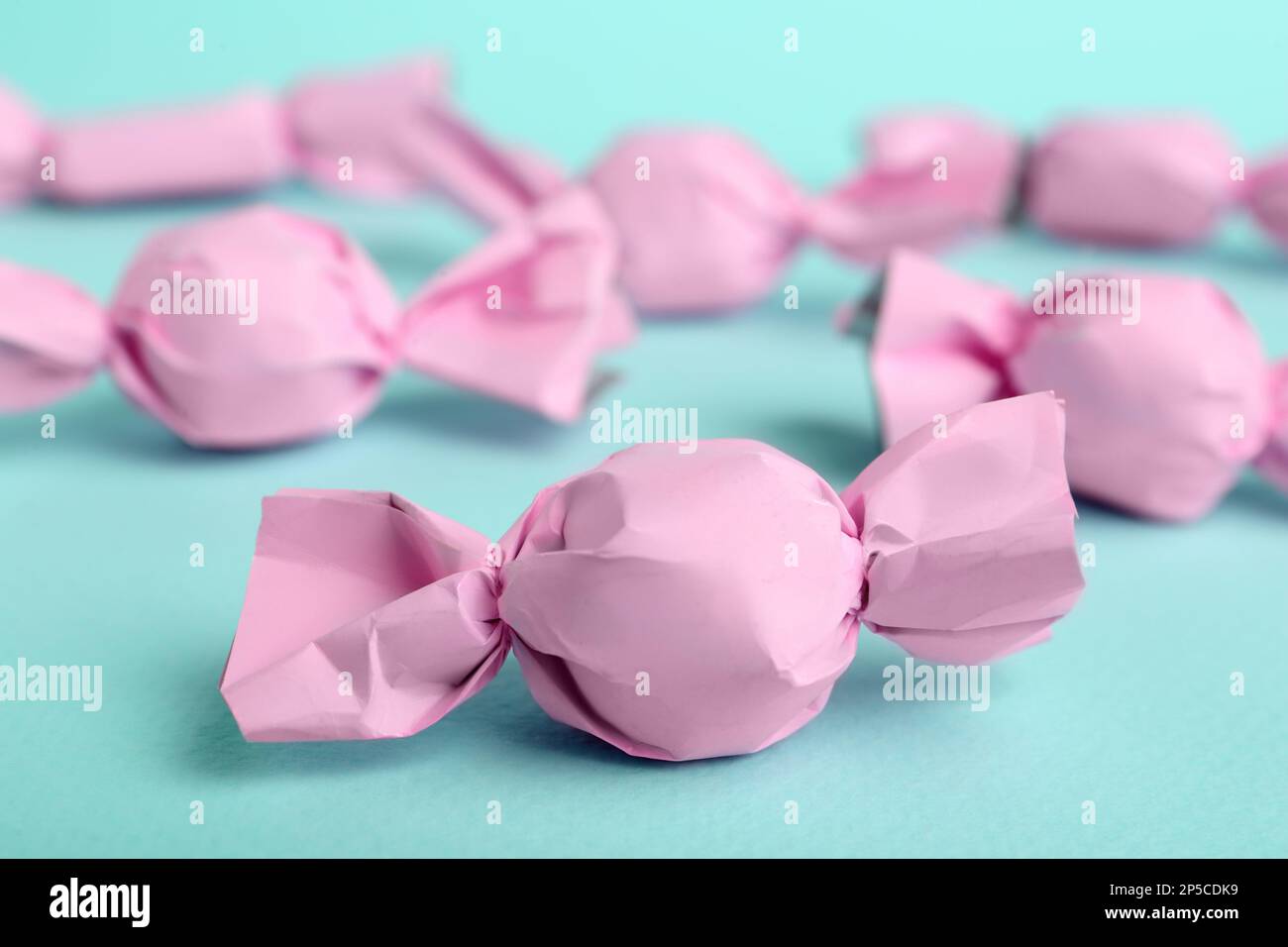 Candies in pink wrappers on light blue background, closeup Stock Photo ...