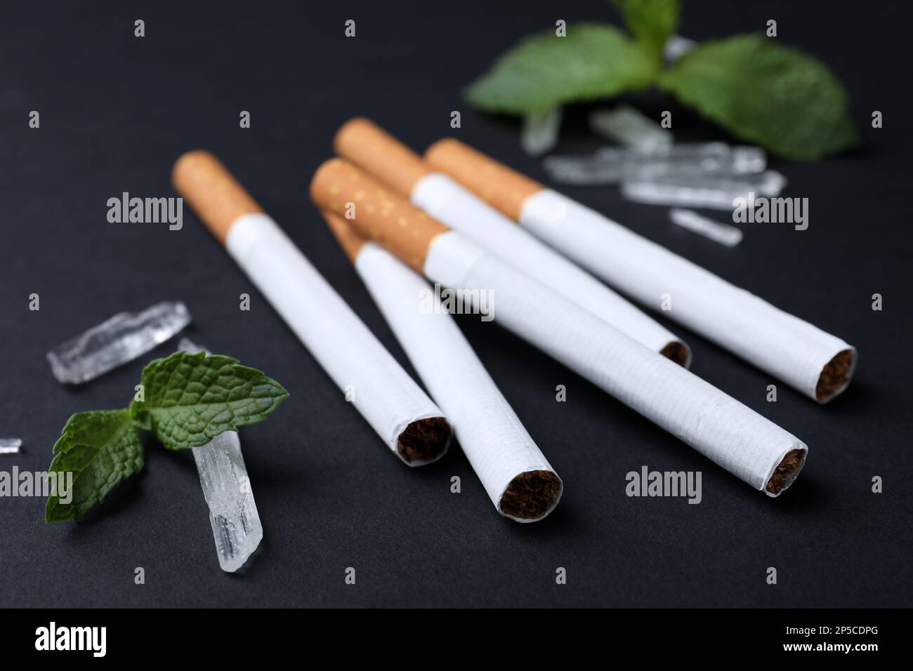Cigarettes, menthol crystals and mint on black background, closeup ...