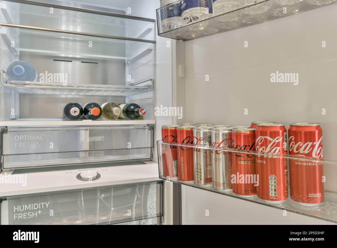 an open refrigerator with sodas and cans on the door, in front of it is ...
