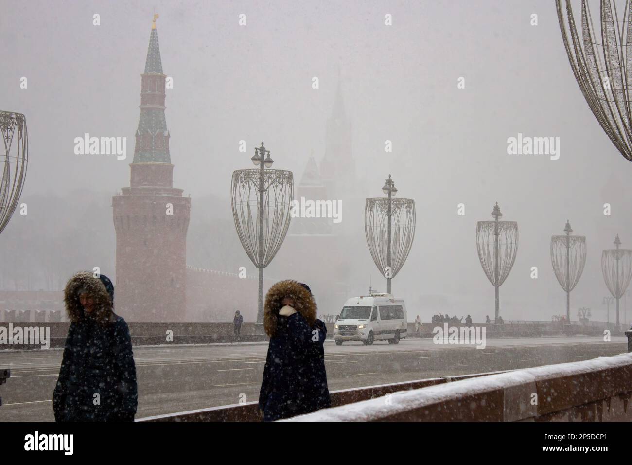 People walk along the Bolshoi Moskvoretsky Bridge with The Kremlin seen ...