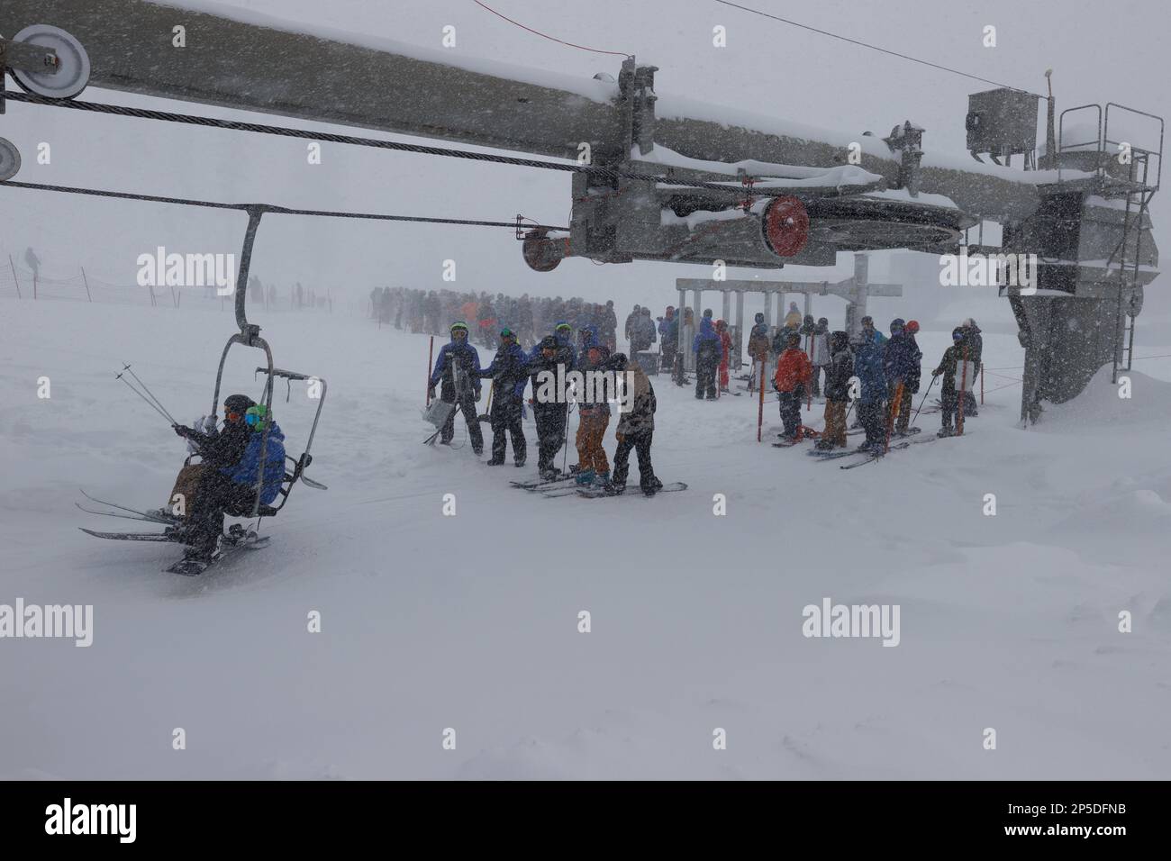 Skiers and snowboarders line up to board a chairlift during a winter ...