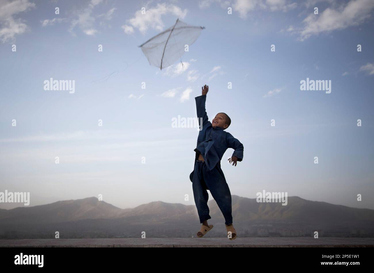 An Afghan boy flies his kite on a hill overlooking Kabul, Afghanistan ...