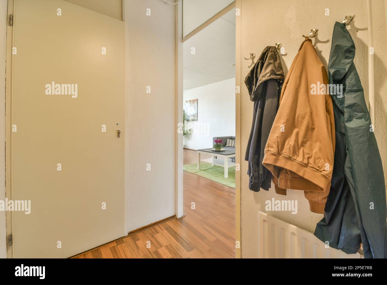 the inside of a house with clothes hanging on hooks, and a door to ...