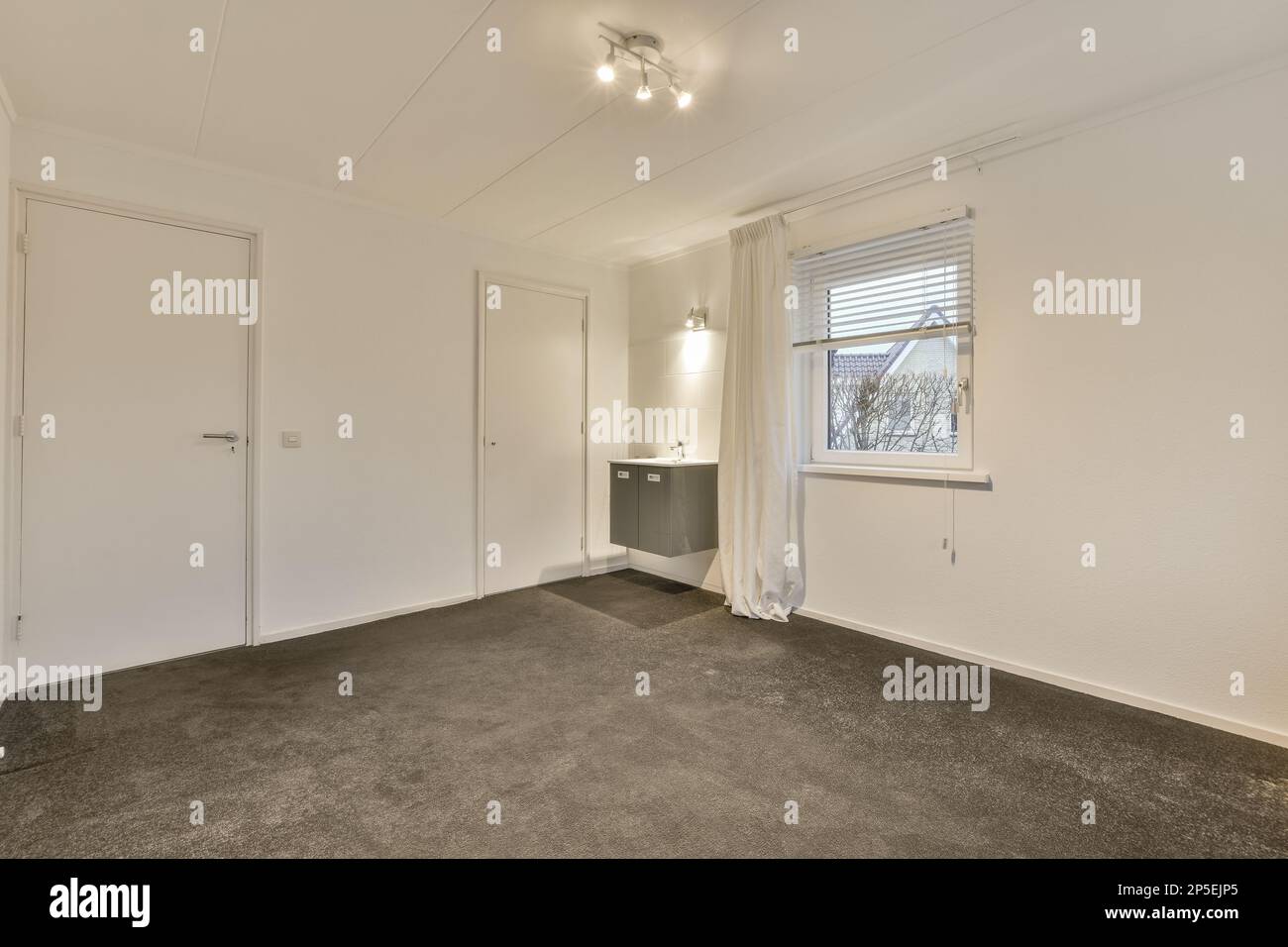 an empty room with white walls and grey flooring, there is a window in ...