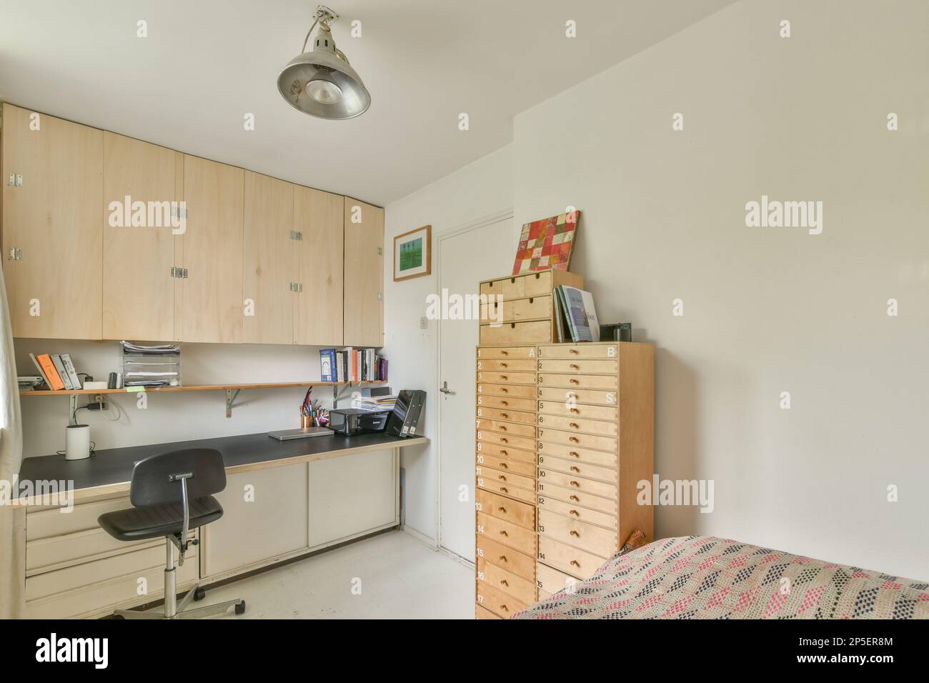 a bedroom with a bed, desk and computer monitor on the wall in front of ...