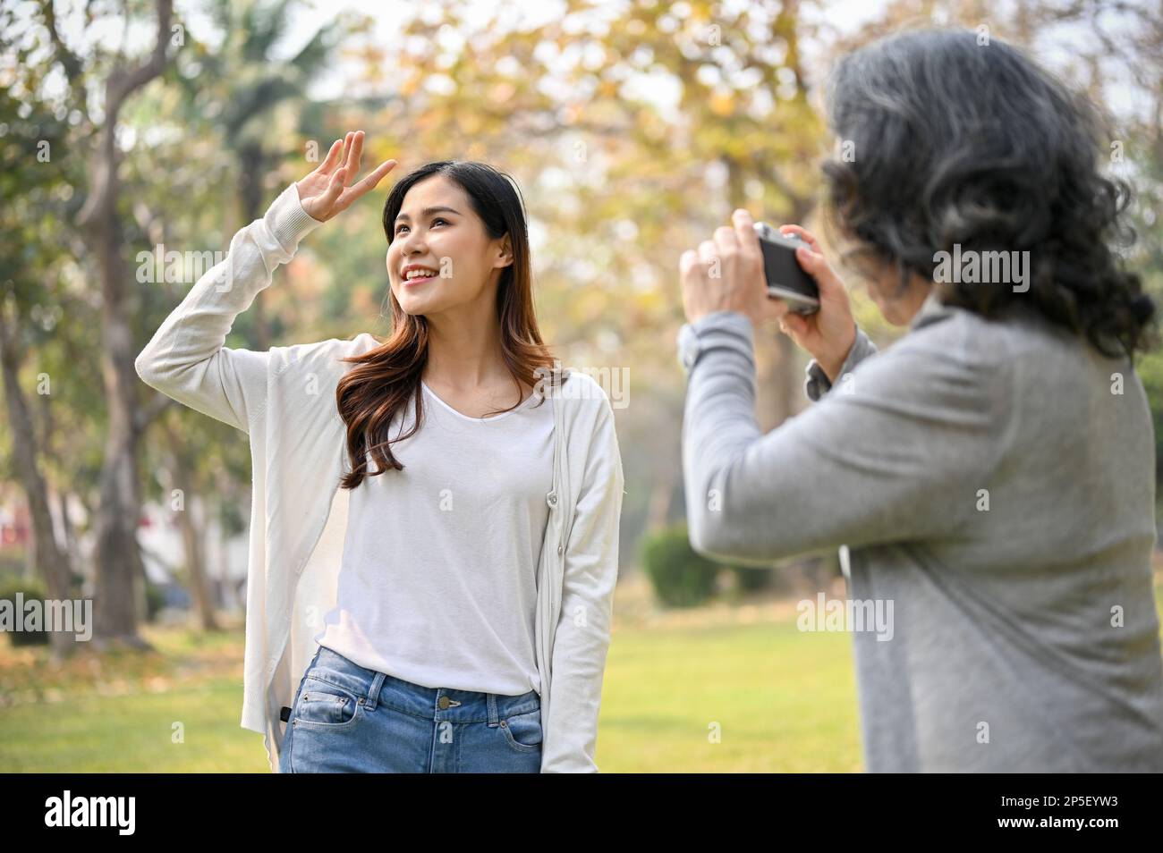 Happy Asian grandma taking a picture of her beautiful granddaughter ...