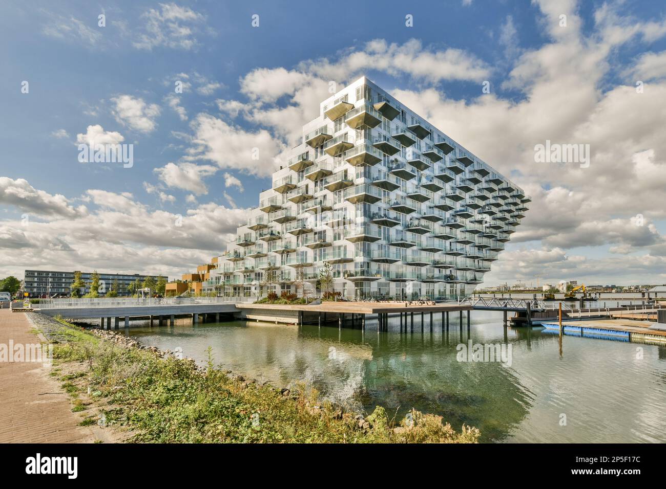 an apartment complex on the water's edge with boats docked in the fore ...