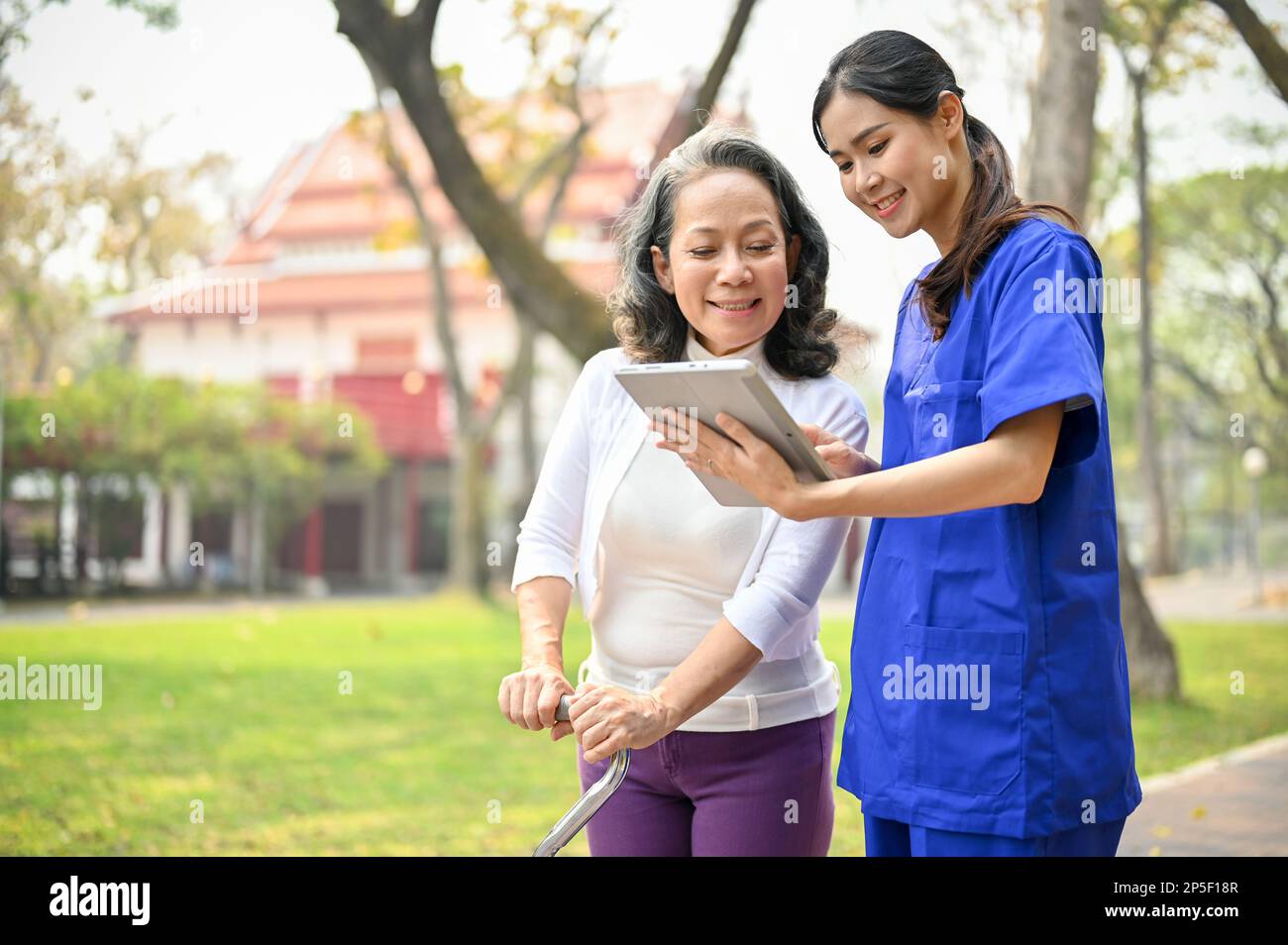 A beautiful and caring young Asian female nurse or caregiver is talking ...