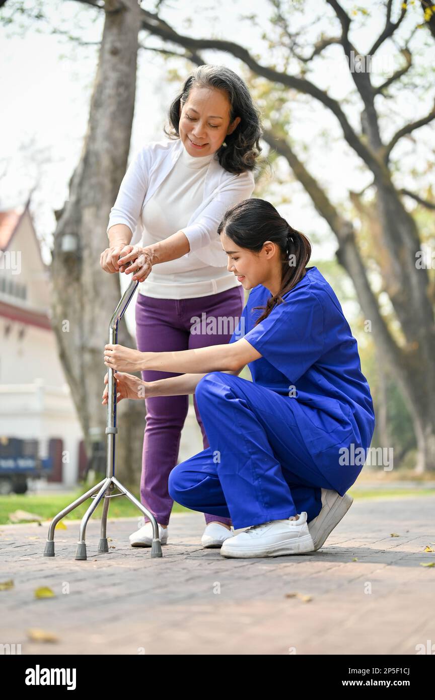 Caring Asian female caregiver or nurse assisting and supporting an old ...