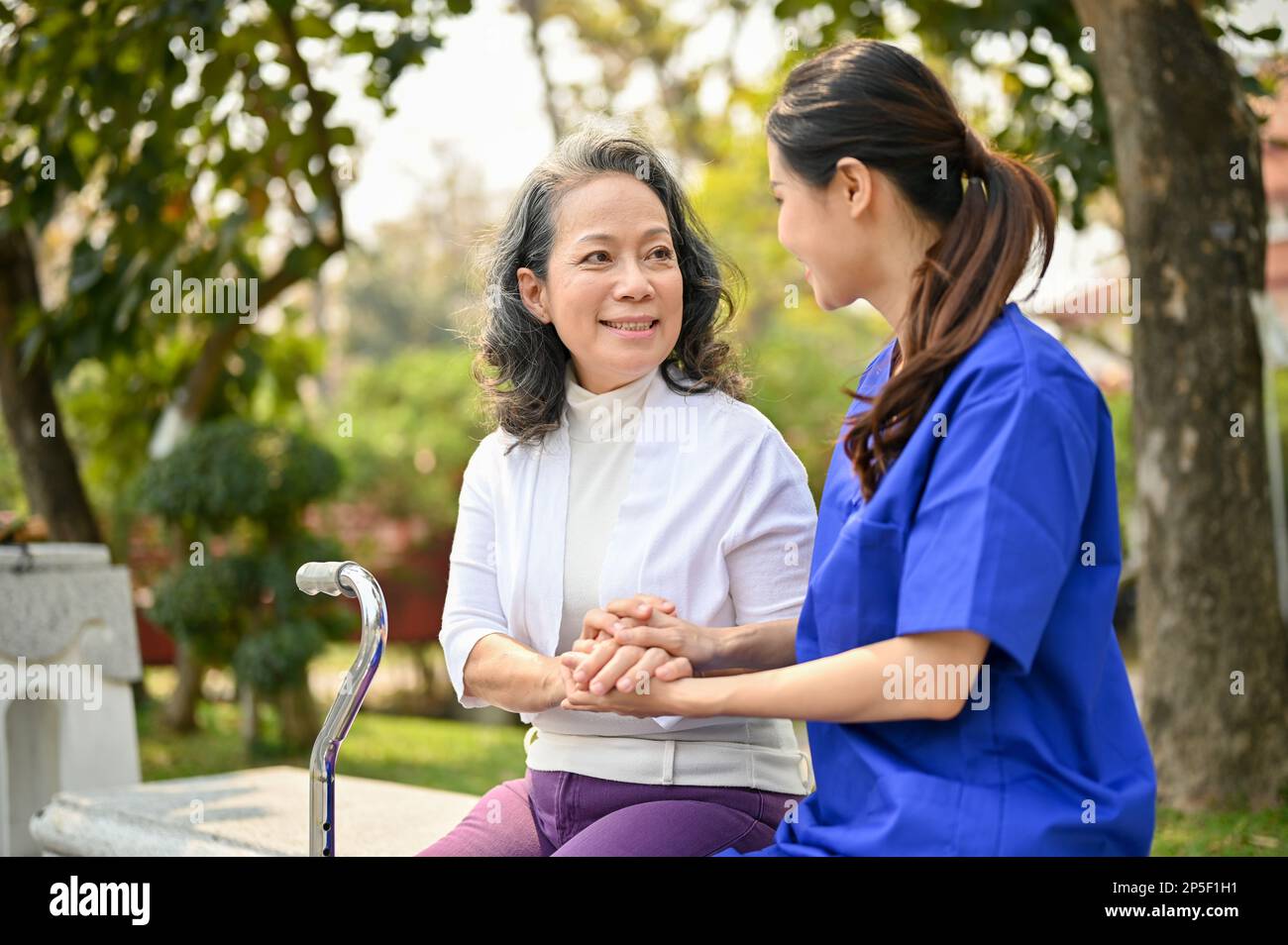 Caring and lovely Asian female nurse or caregiver holding an old female ...