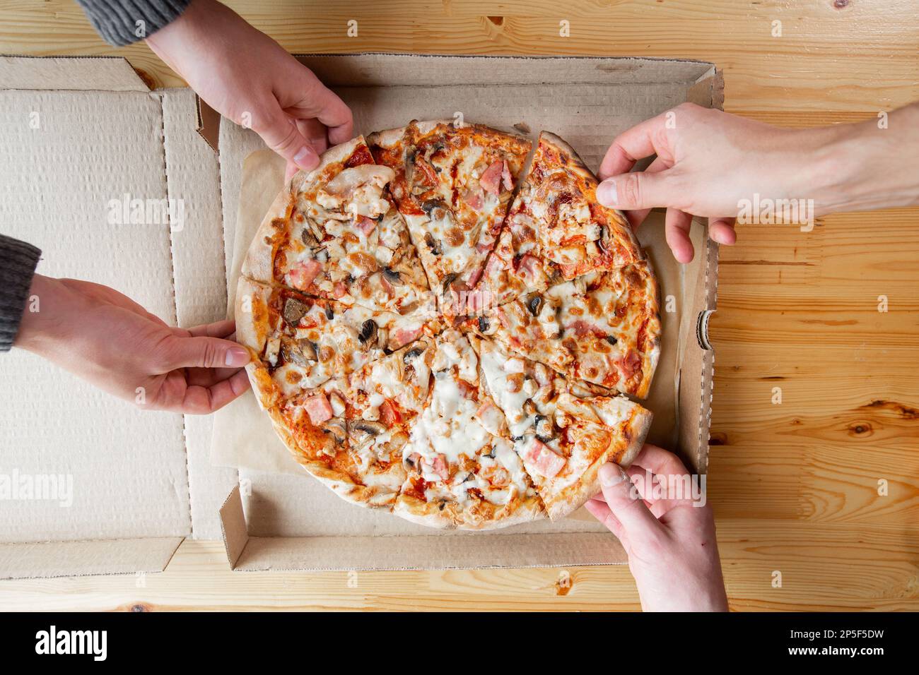 three people taking slices of pizza out of the box. fast delivery of ...