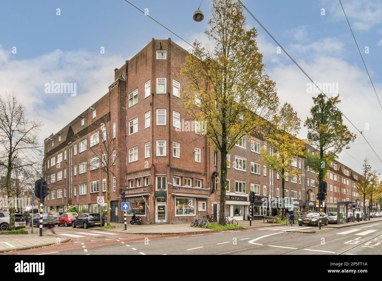 a street corner with cars parked on the side and people walking down ...
