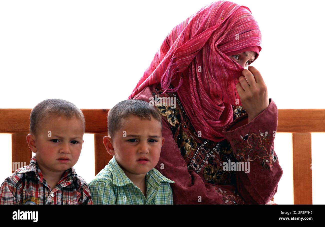 A newly-arrived Syrian refugee woman covers her face as she sits on a ...